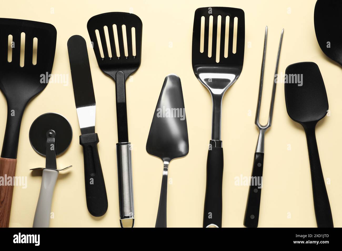 Different spatulas and other kitchen utensils on beige background, flat ...