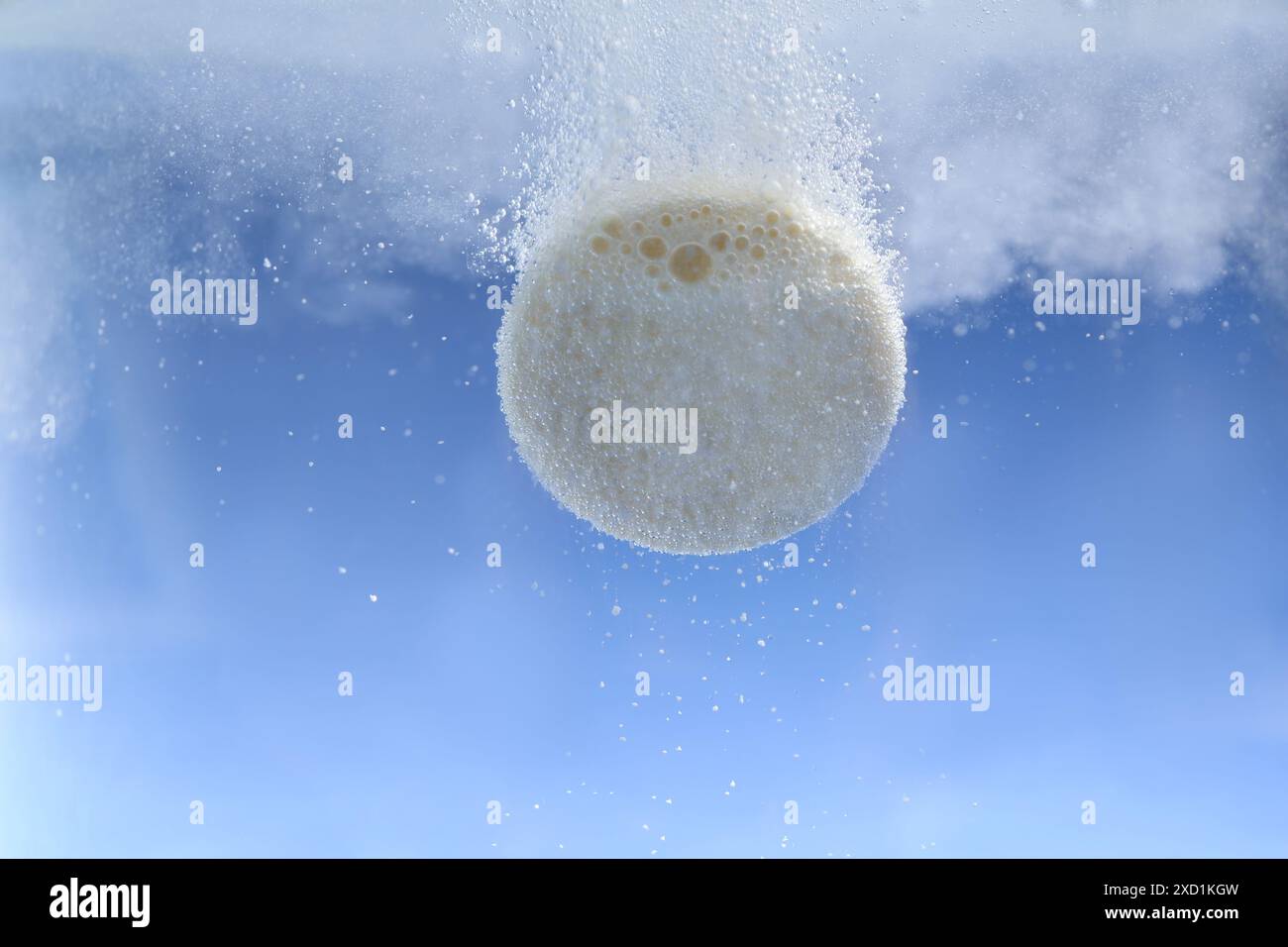 Effervescent pill dissolving in water on light blue background, closeup ...