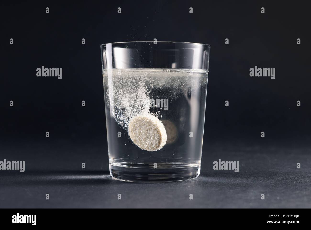Effervescent pill dissolving in glass of water on grey table Stock ...