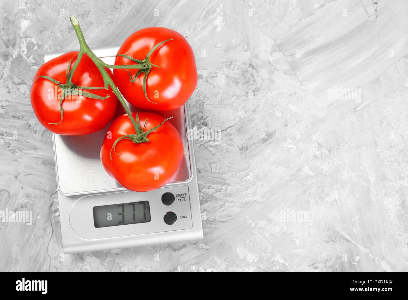 Kitchen scale with tomatoes on grey textured table, top view. Space for ...