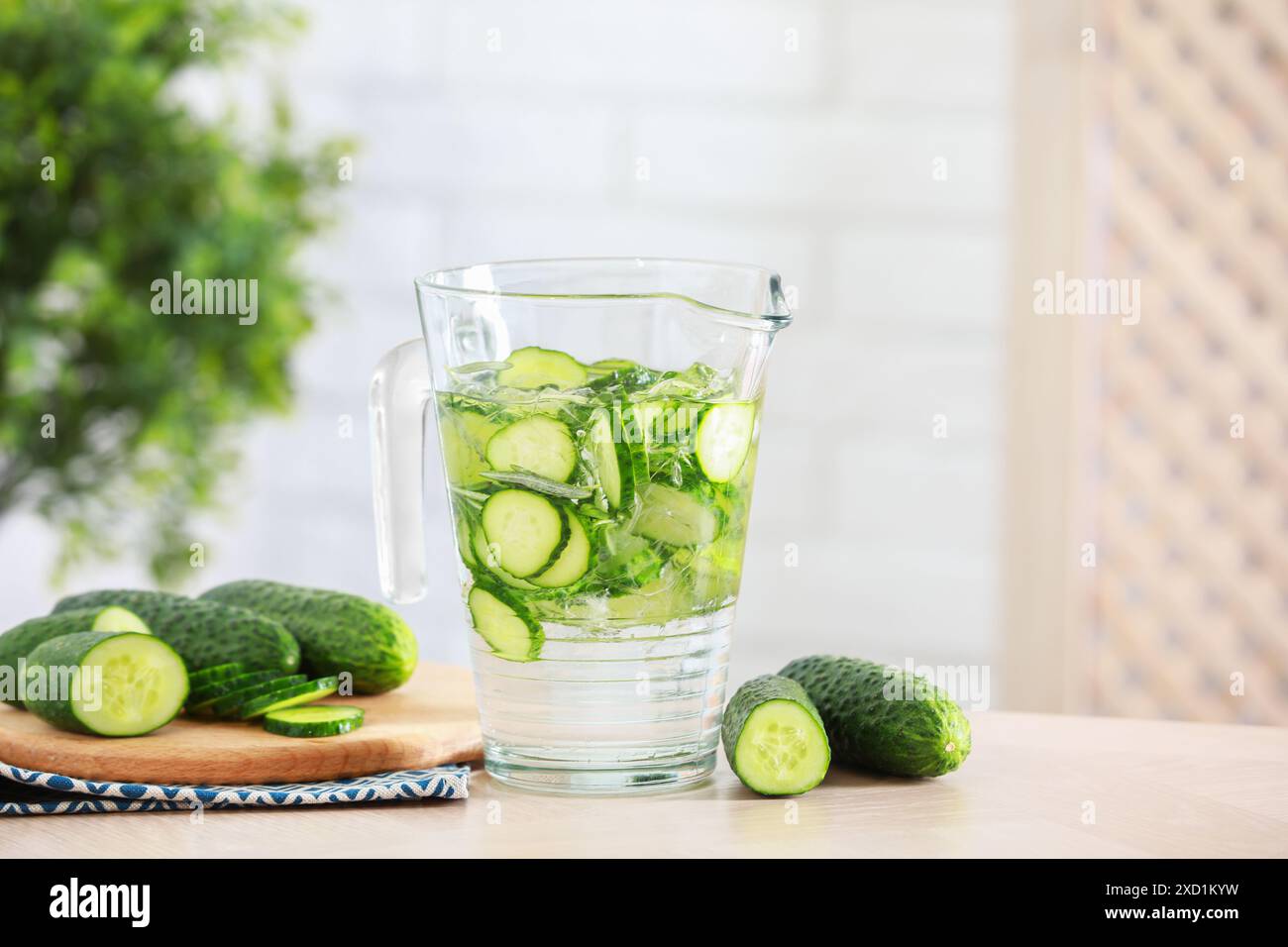Refreshing cucumber water in jug and vegetables on light wooden table. Space for text Stock ...