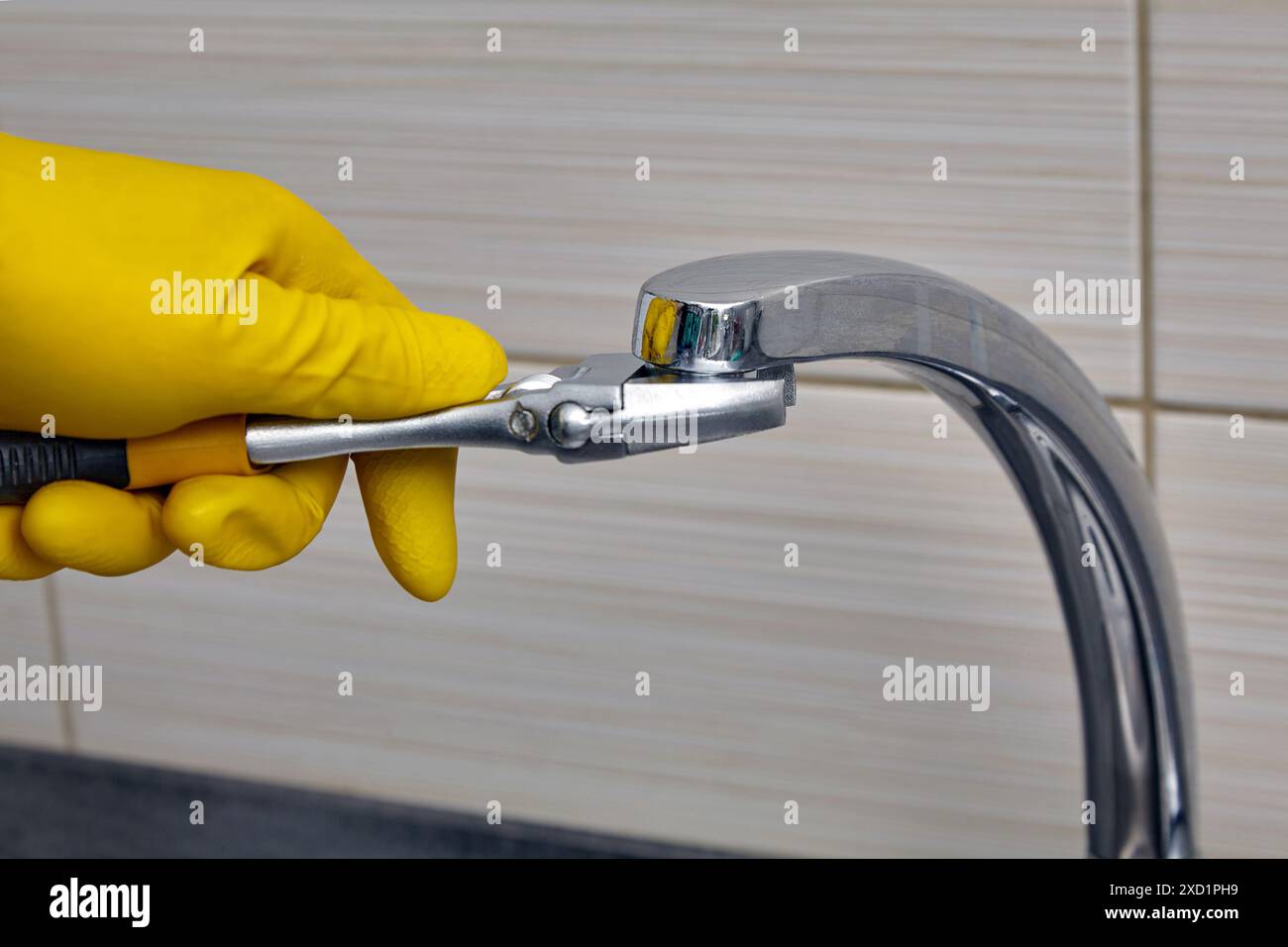A plumber wearing yellow rubber gloves changes the faucet aerator ...