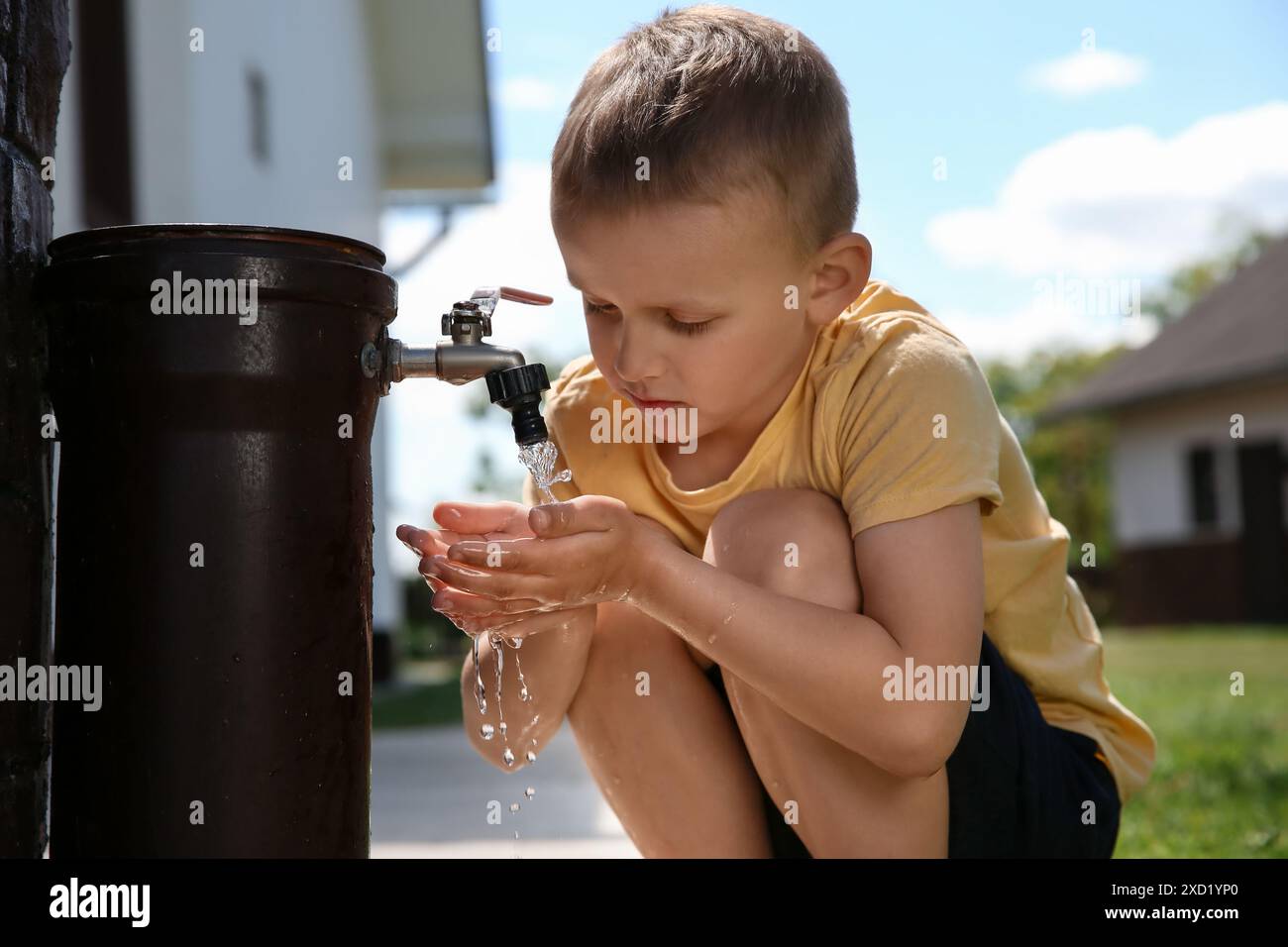 Water scarcity. Cute little boy drawing water with hands from tap ...