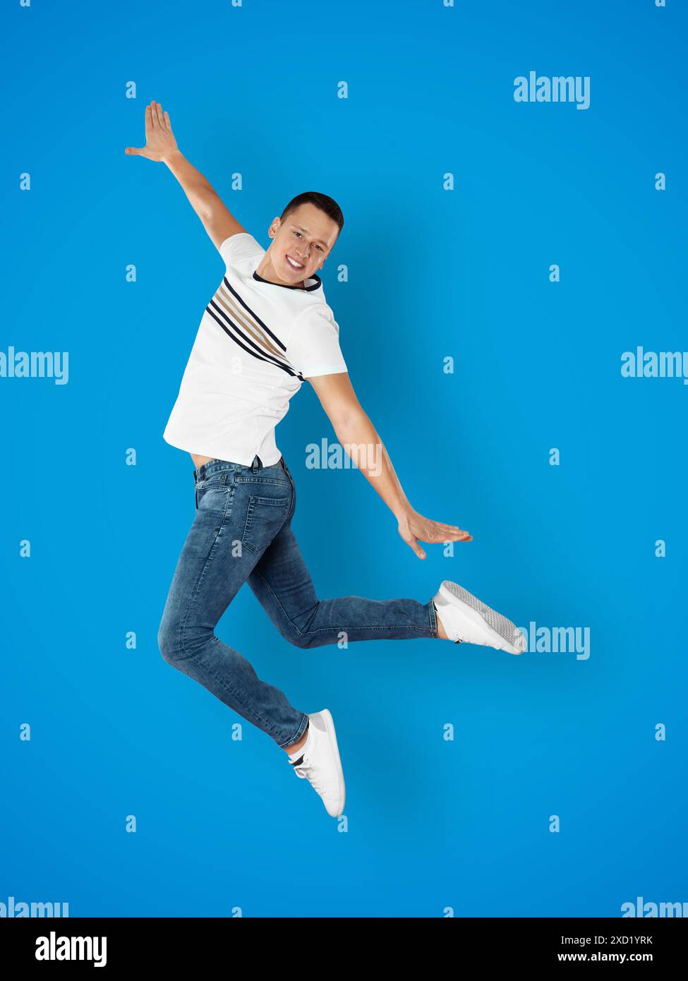 Positive young man jumping on blue background Stock Photo - Alamy