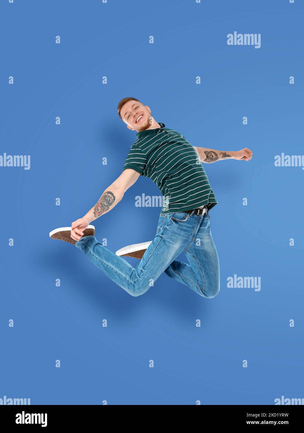 Positive young man jumping on blue background Stock Photo - Alamy