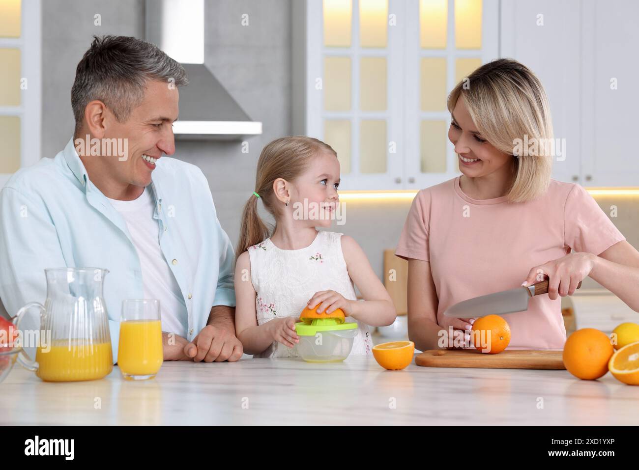 Happy family making juice at white marble table in kitchen Stock Photo ...