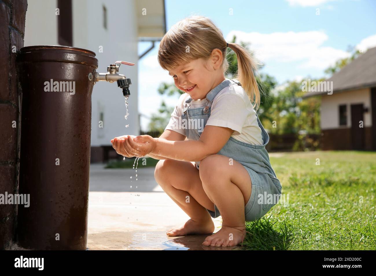 Water scarcity. Cute little girl drawing water with hands from tap ...