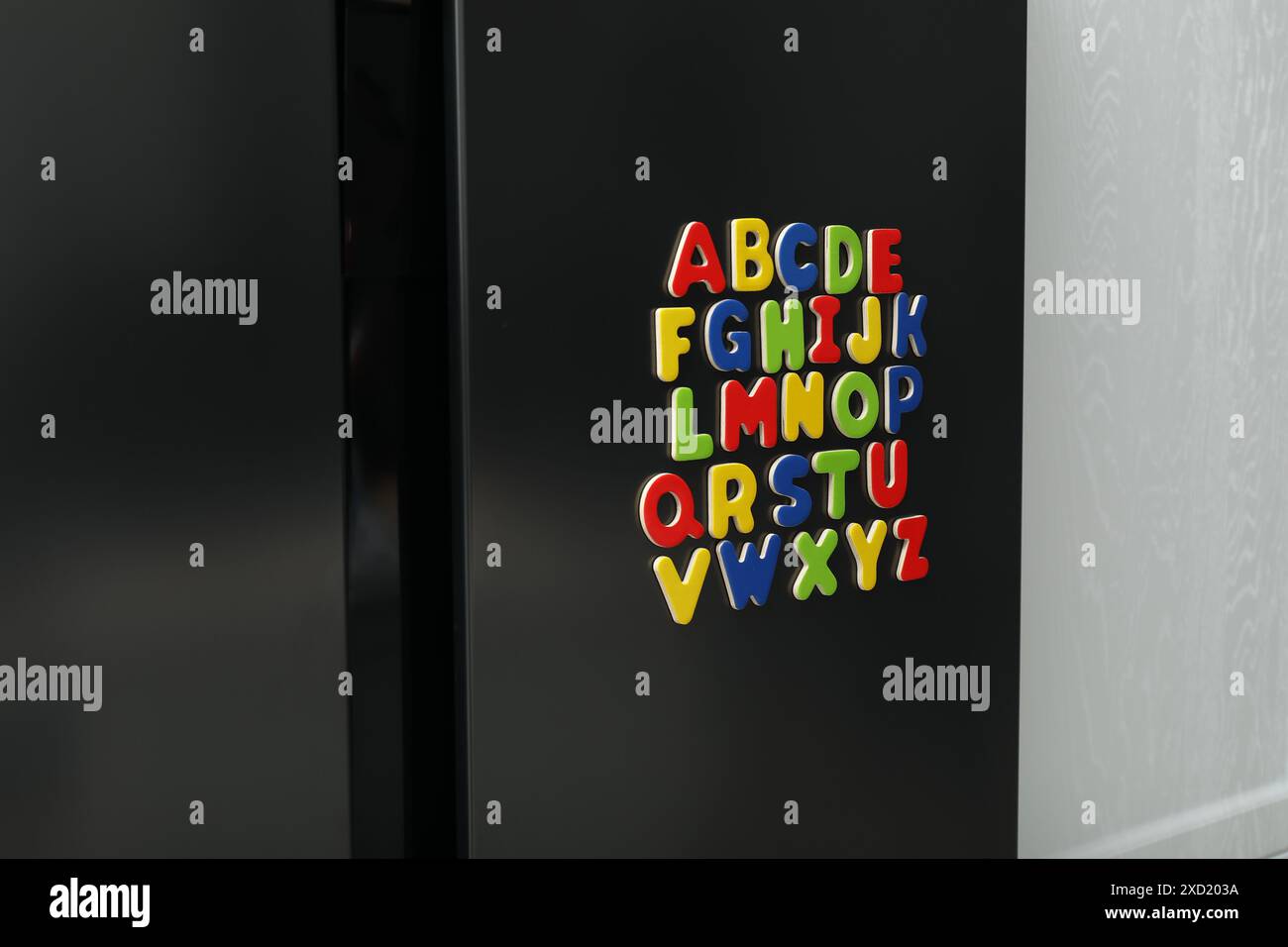 Alphabetical order. Many bright magnetic letters on fridge indoors ...