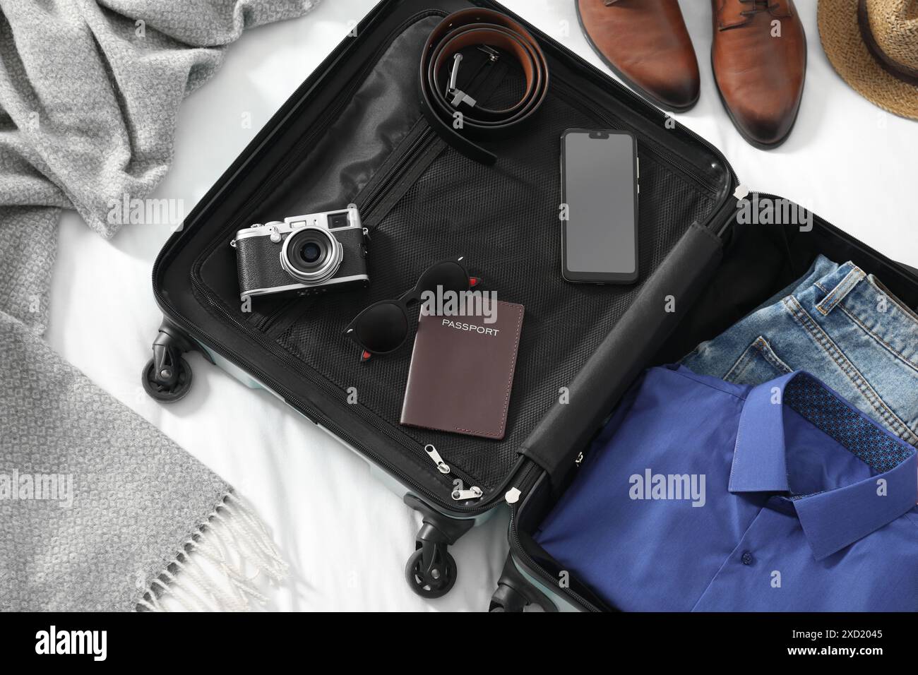 Open suitcase with traveler's belongings on bed, flat lay Stock Photo ...