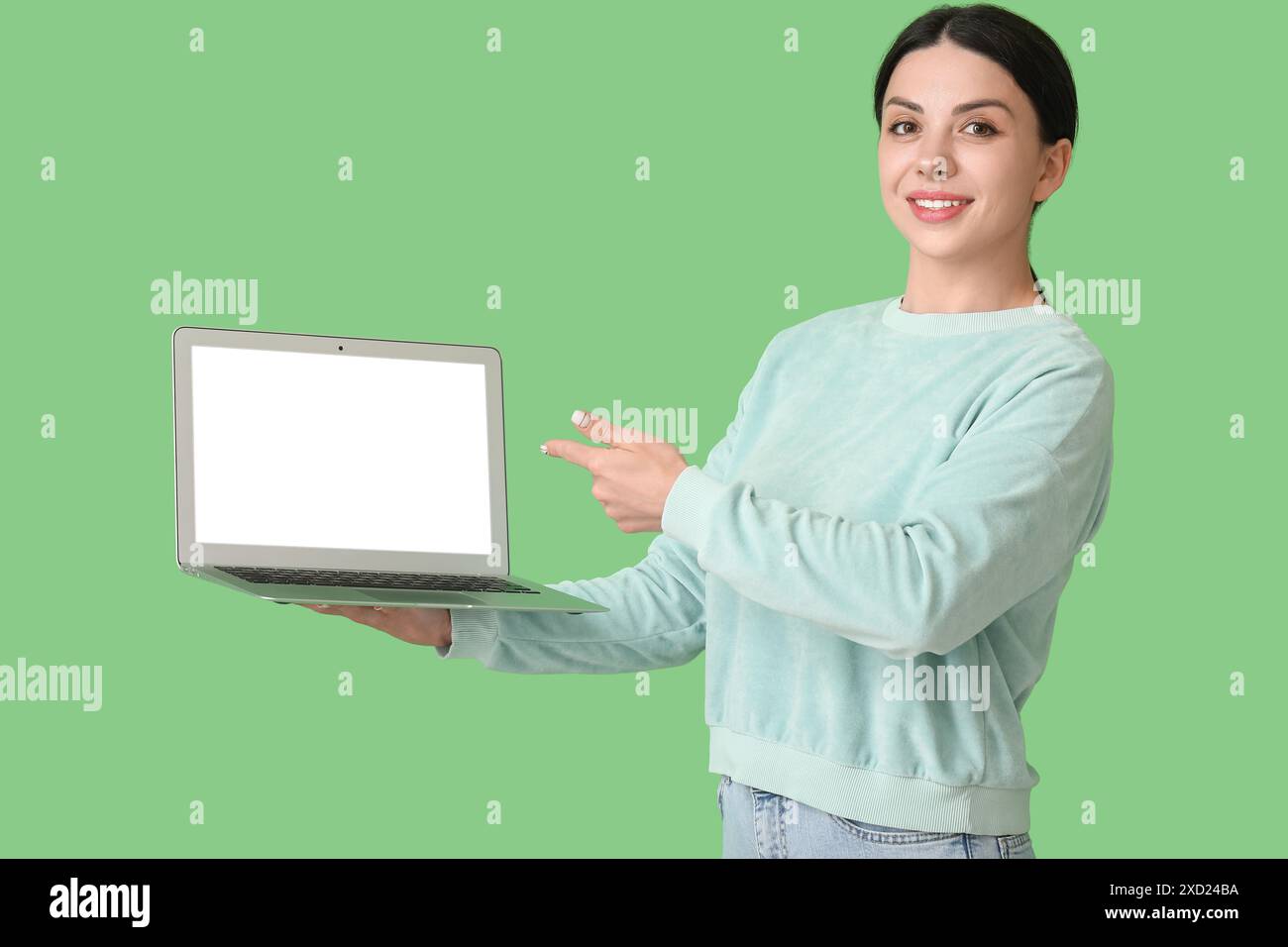 Female programmer pointing at laptop on green background Stock Photo ...