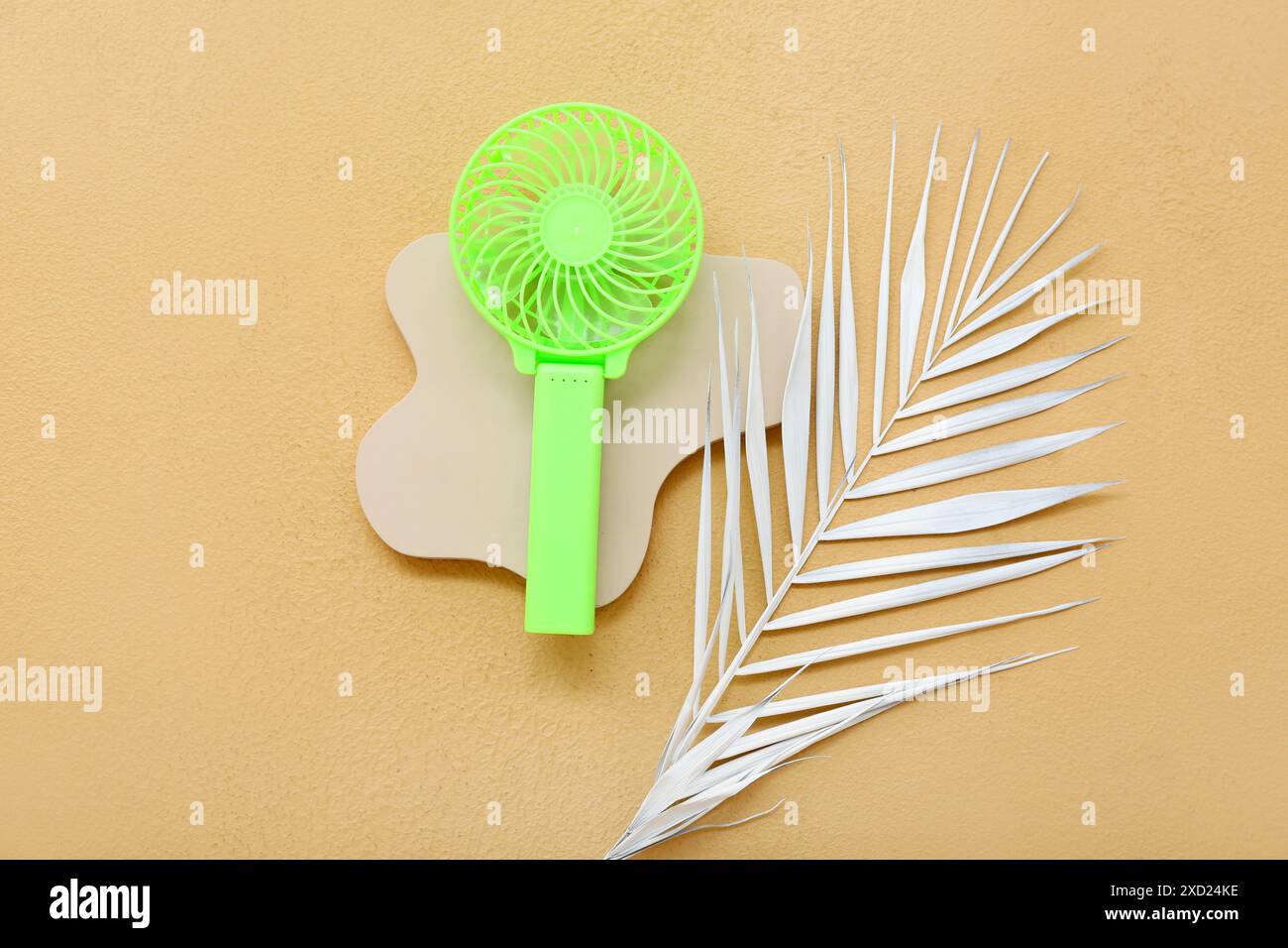 Portable green electric fan and palm leaves on brown background Stock ...