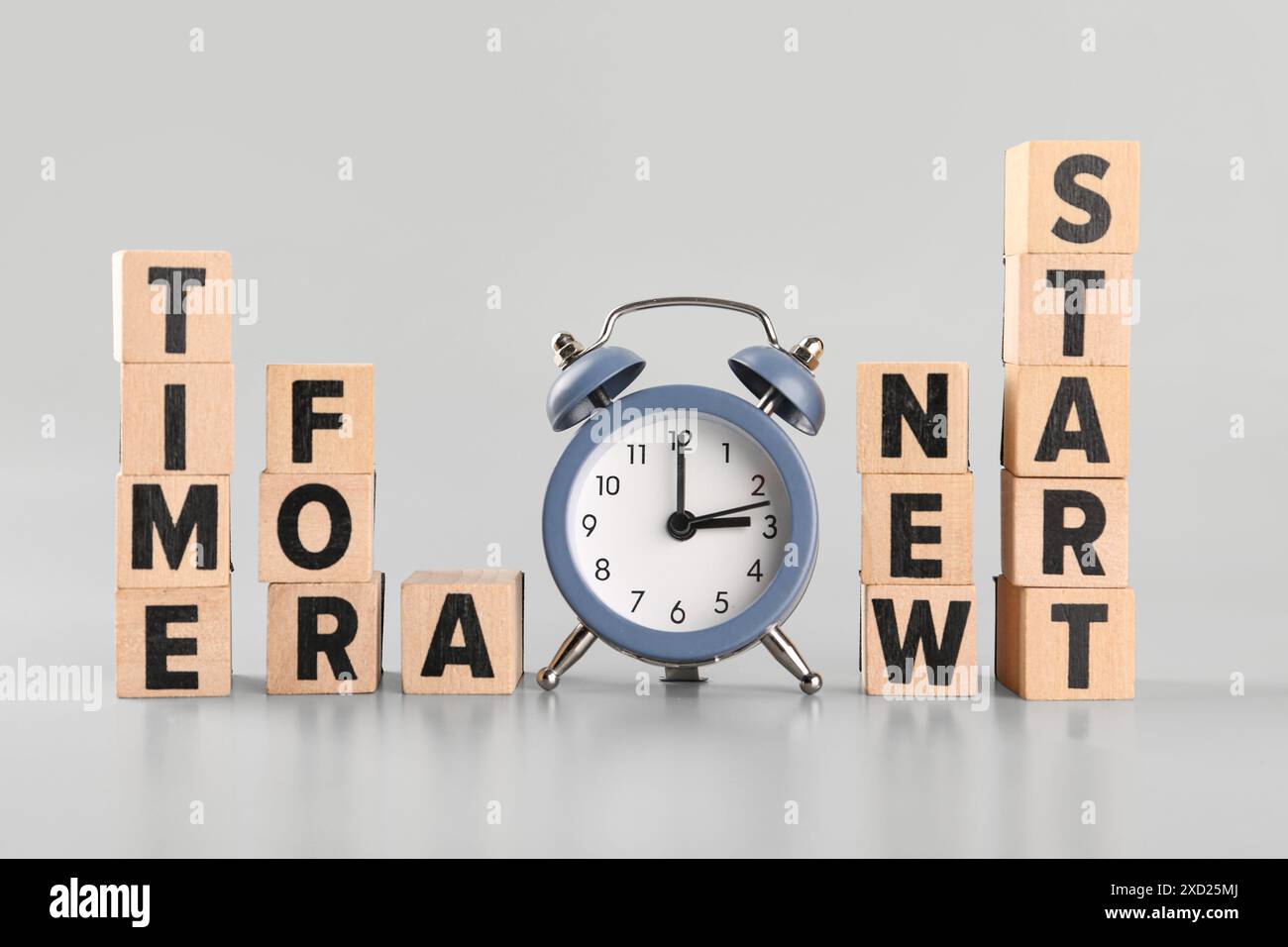 Cubes with text TIME FOR A NEW START and alarm clock on light ...