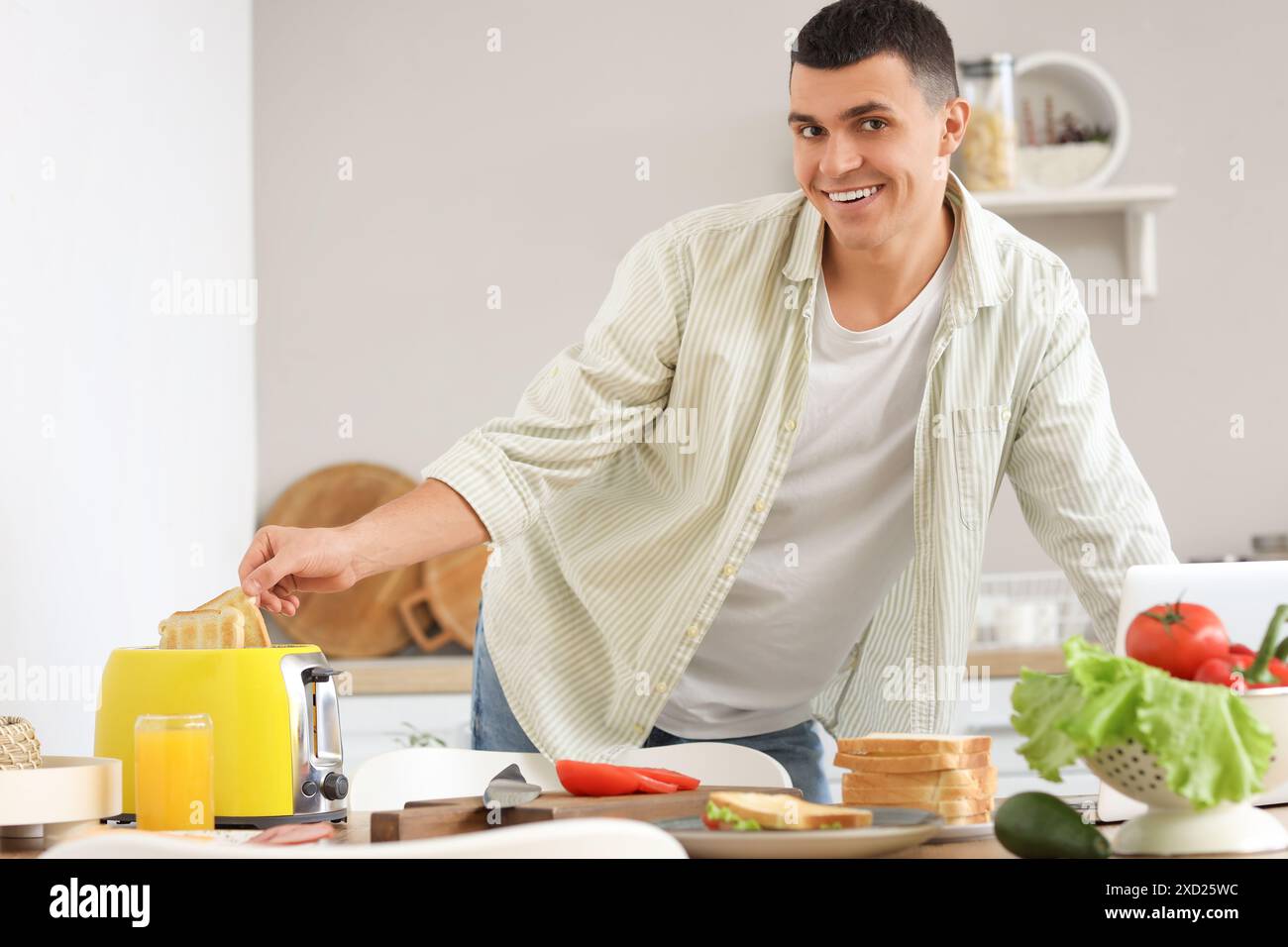 Young man making crispy toasts for sandwiches in kitchen Stock Photo ...
