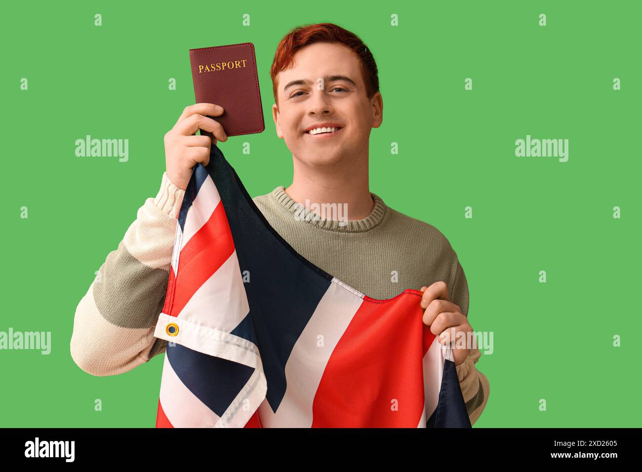 Handsome young happy man with UK flag and passport on green background ...