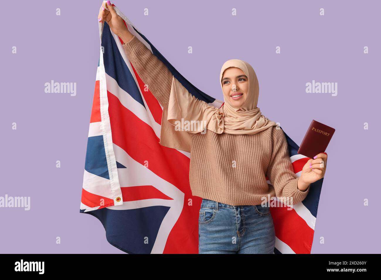 Beautiful young Muslim woman with UK flag and passport on purple ...