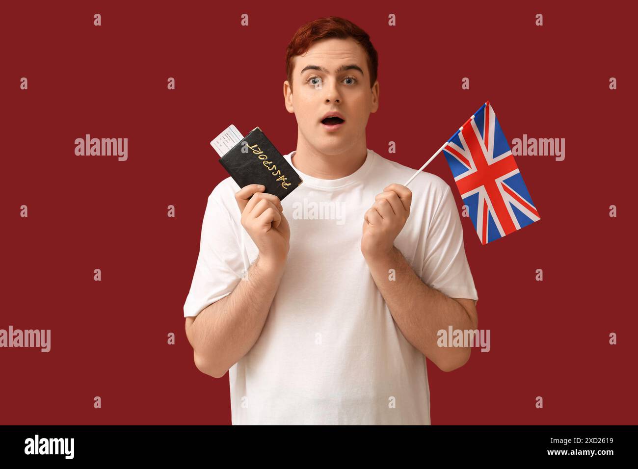 Handsome young shocked man with UK flag, passport and ticket on red ...