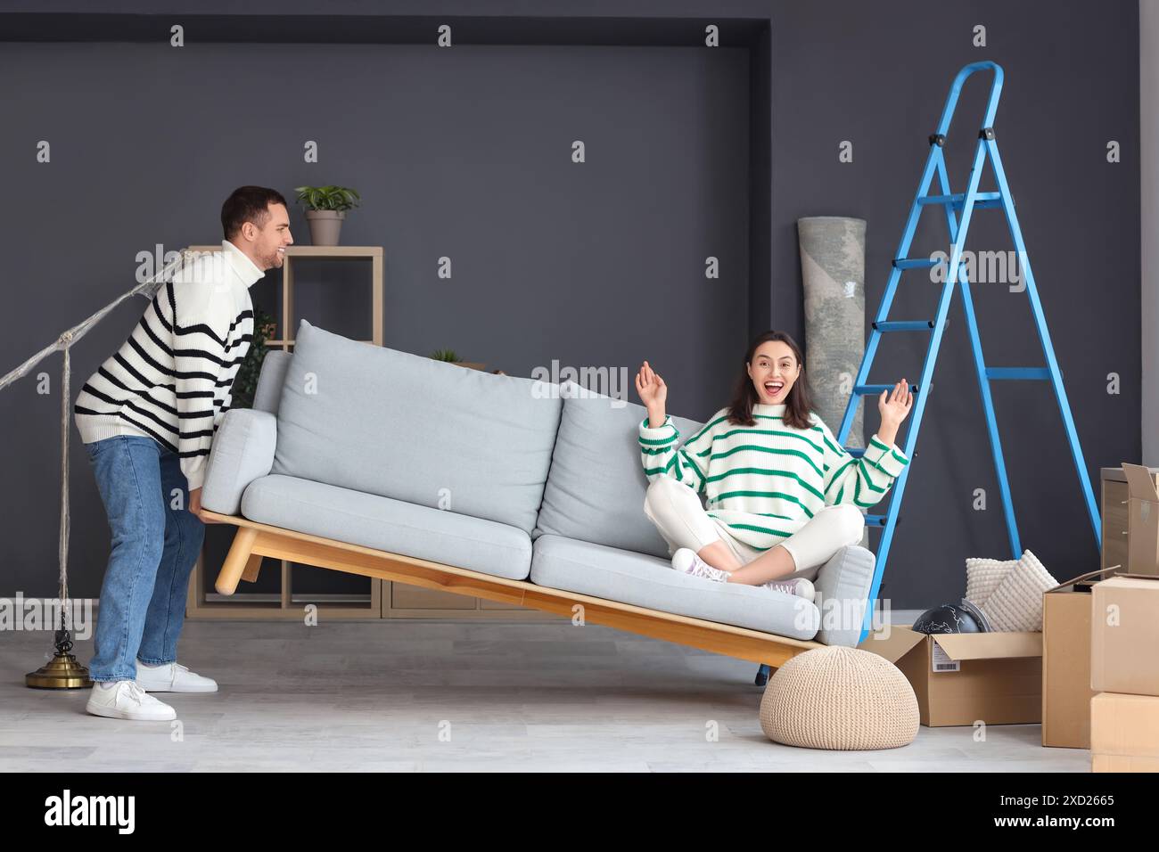 Happy young couple carrying sofa in room on moving day Stock Photo - Alamy