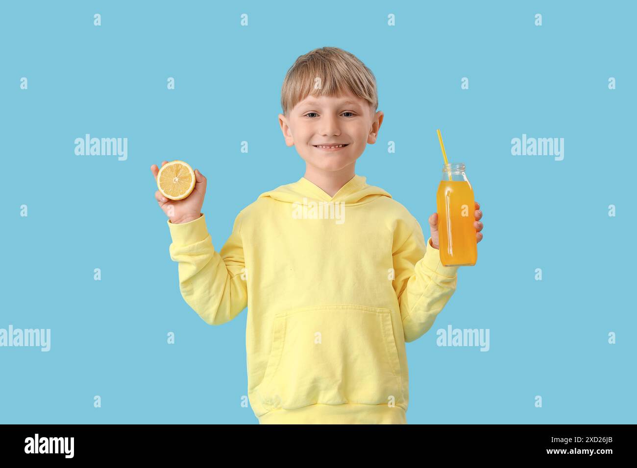 Cute little boy with lemon and bottle of lemonade on blue background ...
