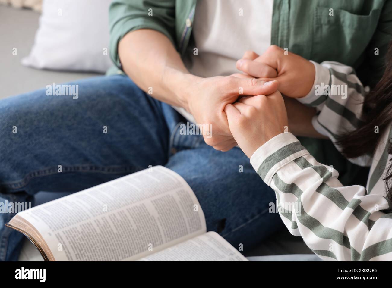 Religious couple with Holy Bible praying on sofa at home, closeup Stock ...