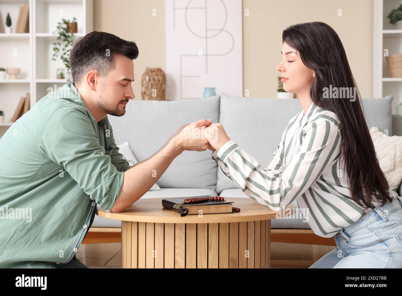 Religious couple with Holy Bible praying at home Stock Photo - Alamy