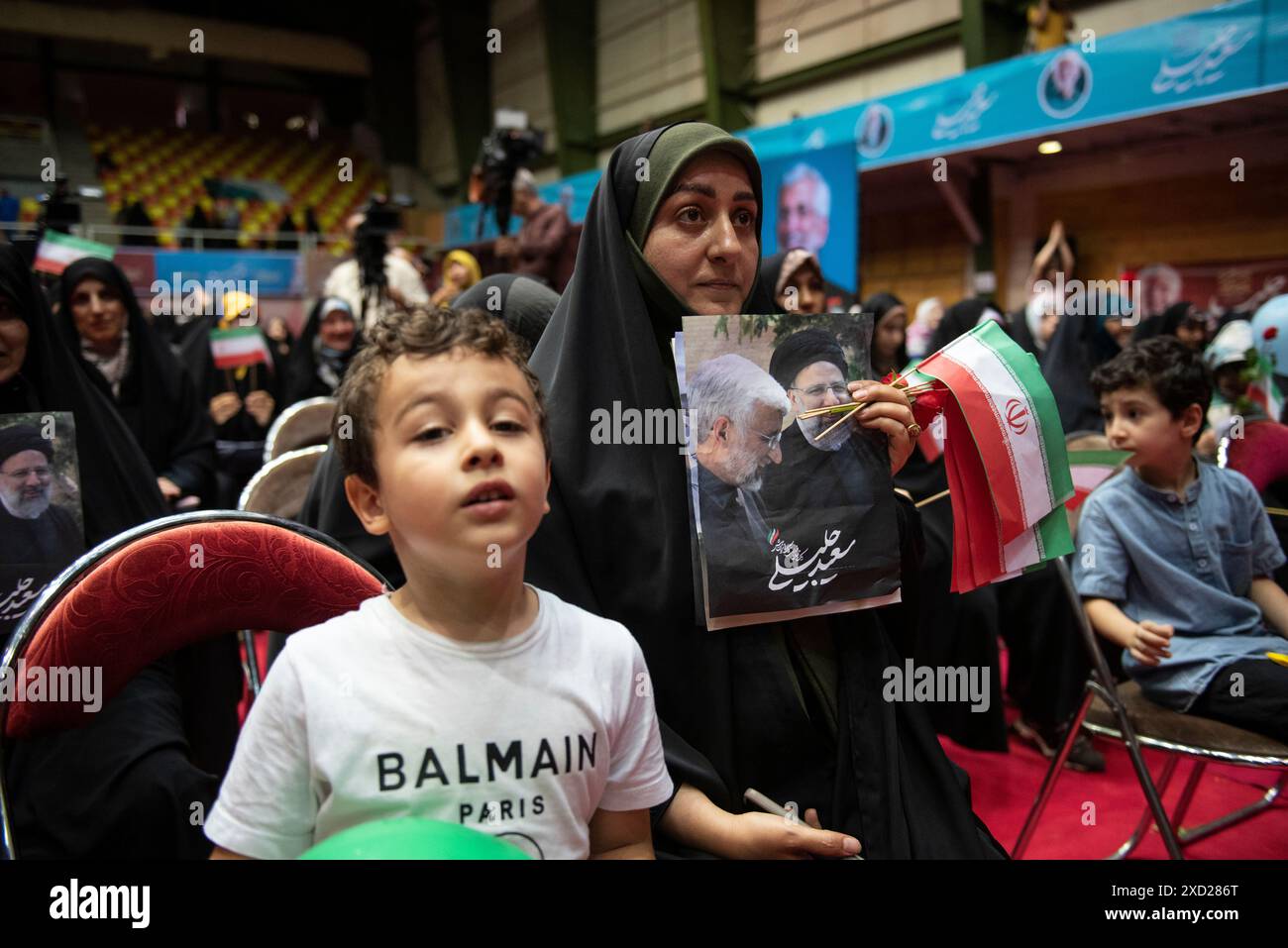 Tehran, Iran. 19th June, 2024. A woman holds up Iranian flags and a poster of Saeed Jalili, the ...