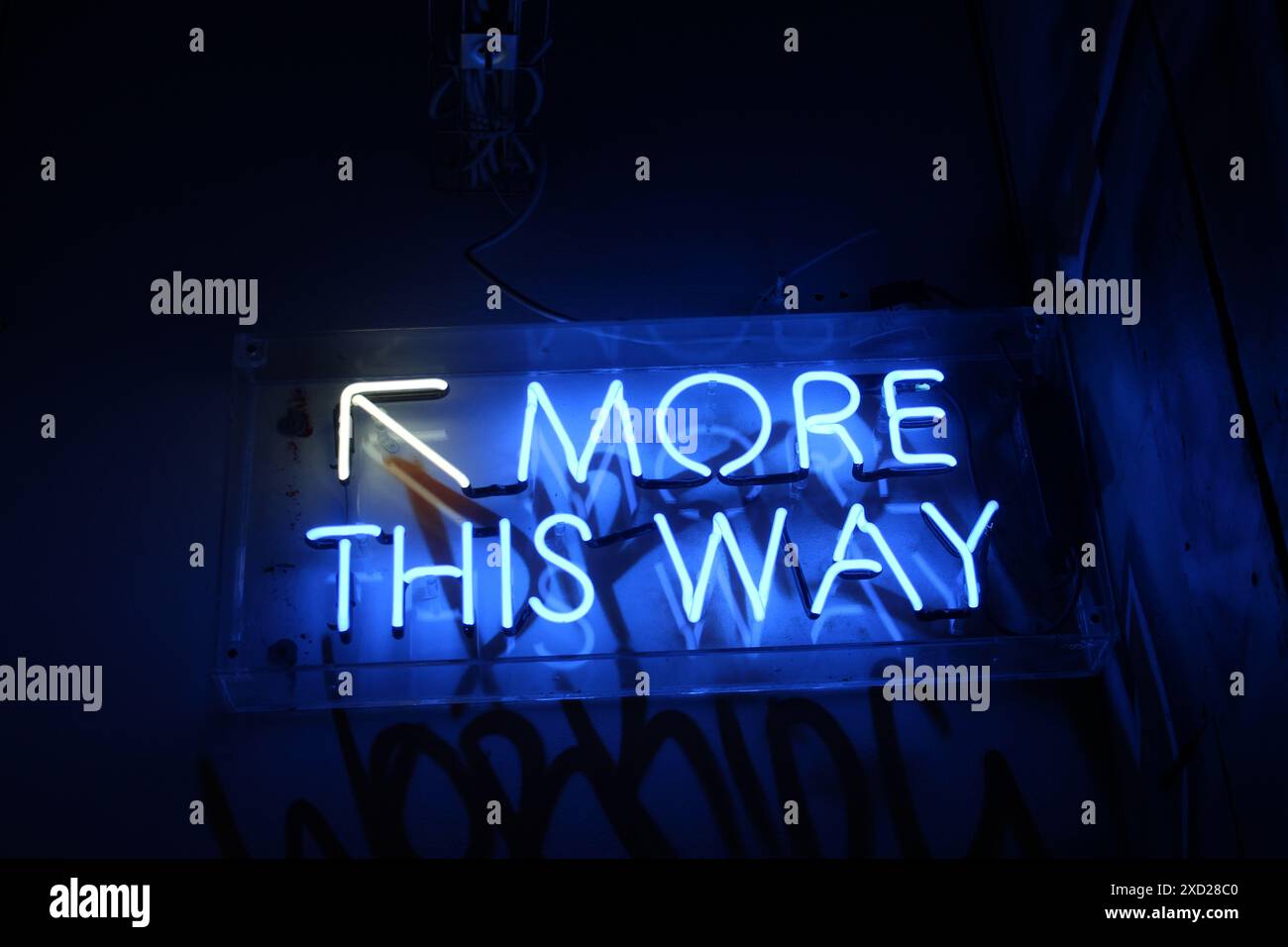 A glowing blue neon sign 'More this way' Stock Photo - Alamy