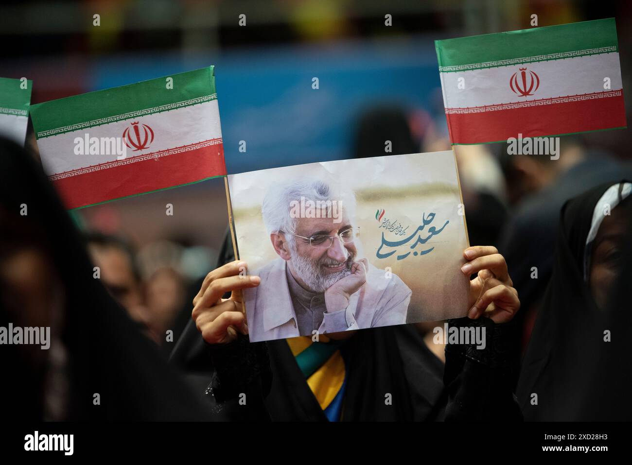 Tehran, Tehran, Iran. 19th June, 2024. A woman holds up Iranian flags and a poster of Saeed ...