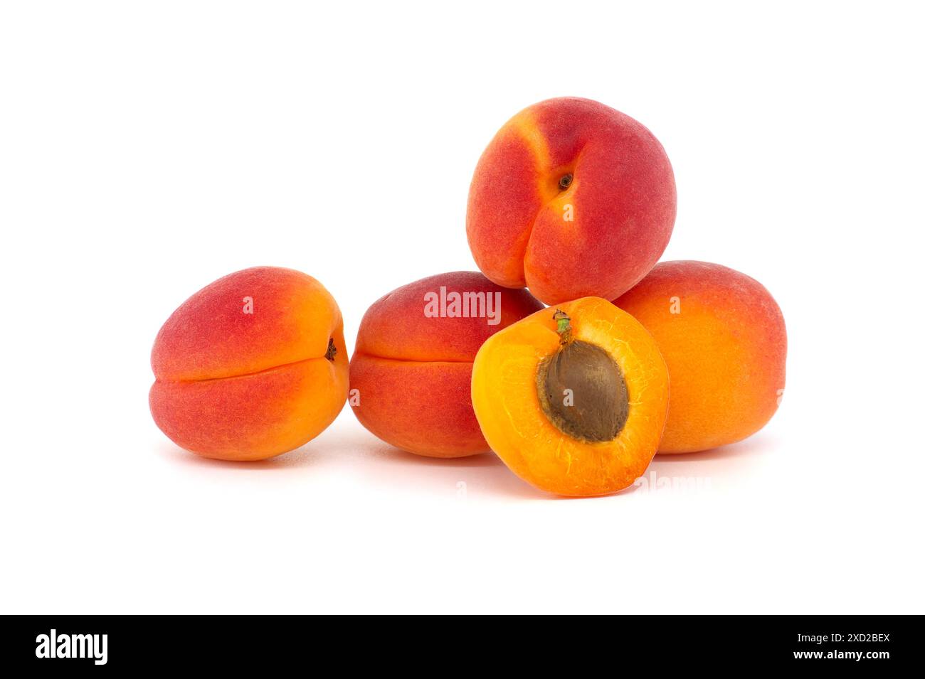 Collection of ripe whole apricots and one cut in half to reveal its ...
