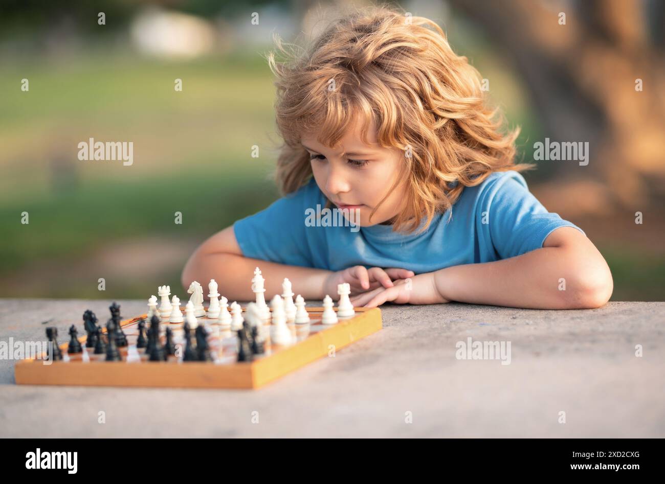 Kid playing chess game in backyard, laying on grass. Concentrated child ...