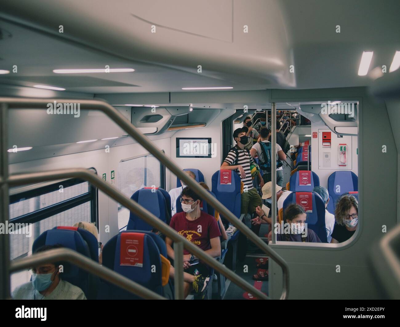 Passengers wearing protective face masks are riding a modern train ...