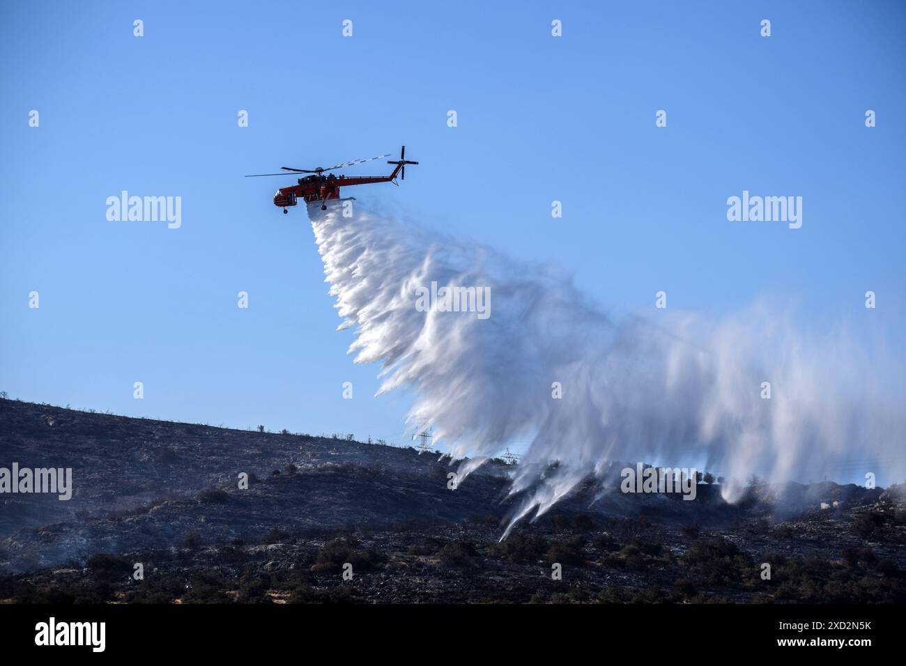 Athens, Greece. 19 June 2024. A firefighting helicopter makes a water ...
