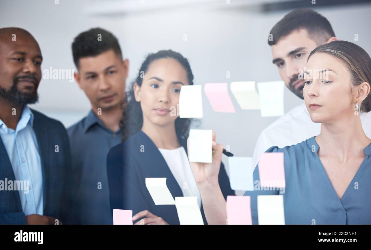 Sticky note, glass wall and business people in office with ...