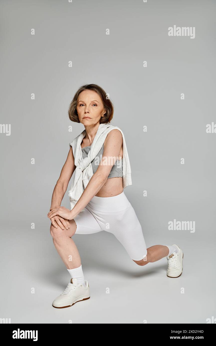 A mature woman squatting gracefully on a white background Stock Photo ...