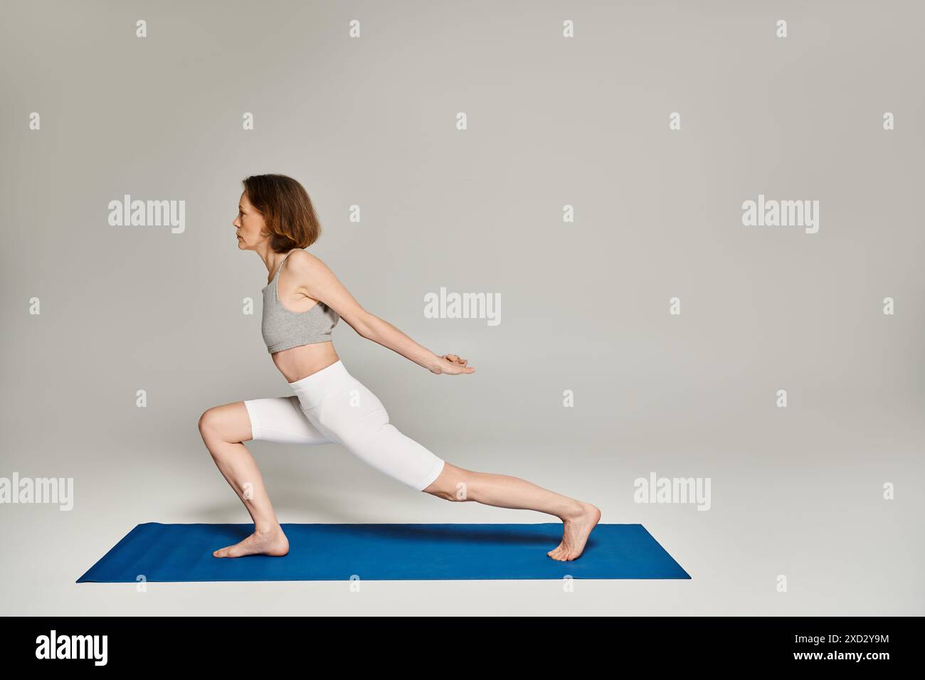 Mature woman in comfy attire engaged in yoga poses on a blue mat Stock ...