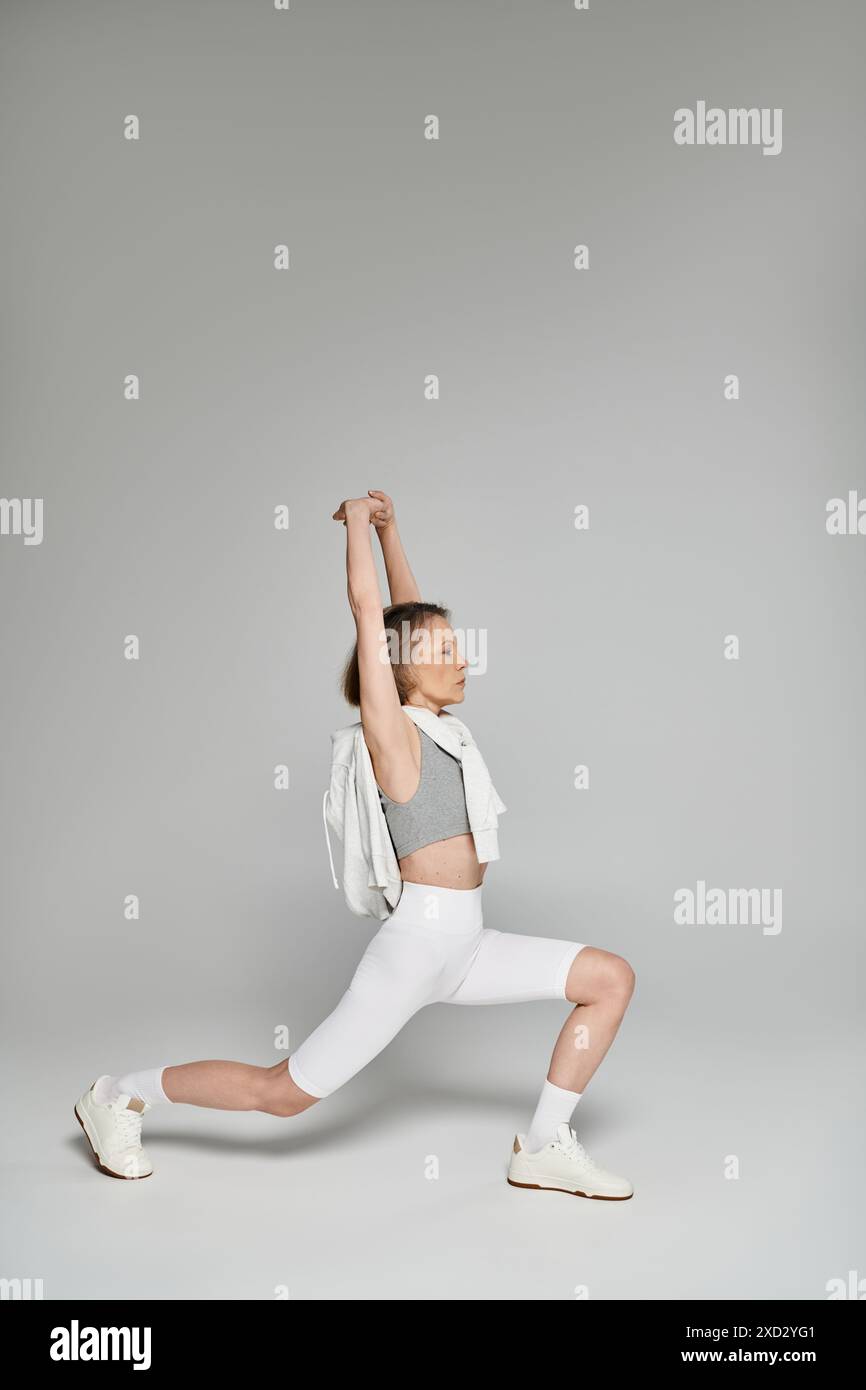 Active woman performing a squat on a grey background Stock Photo - Alamy