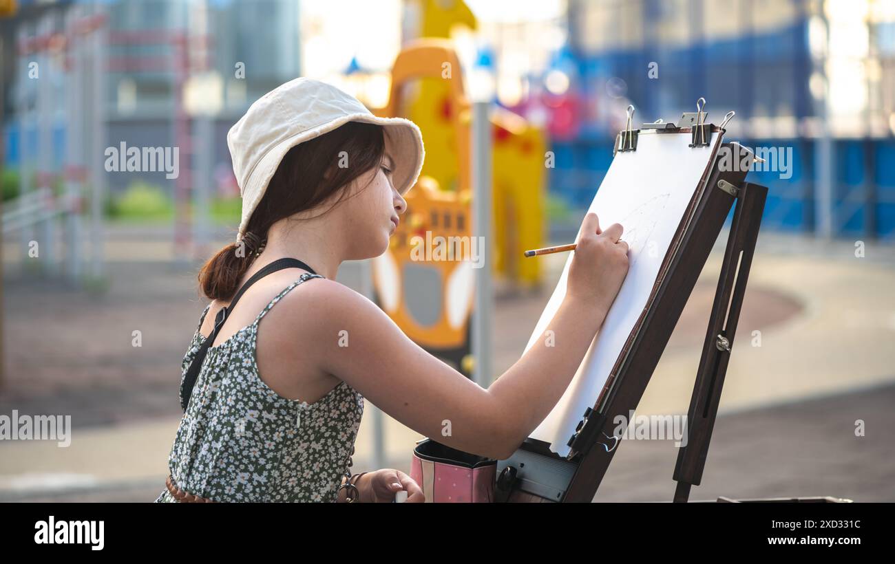 Cute teenage girl drawing at easel outdoors, in the courtyard of the ...
