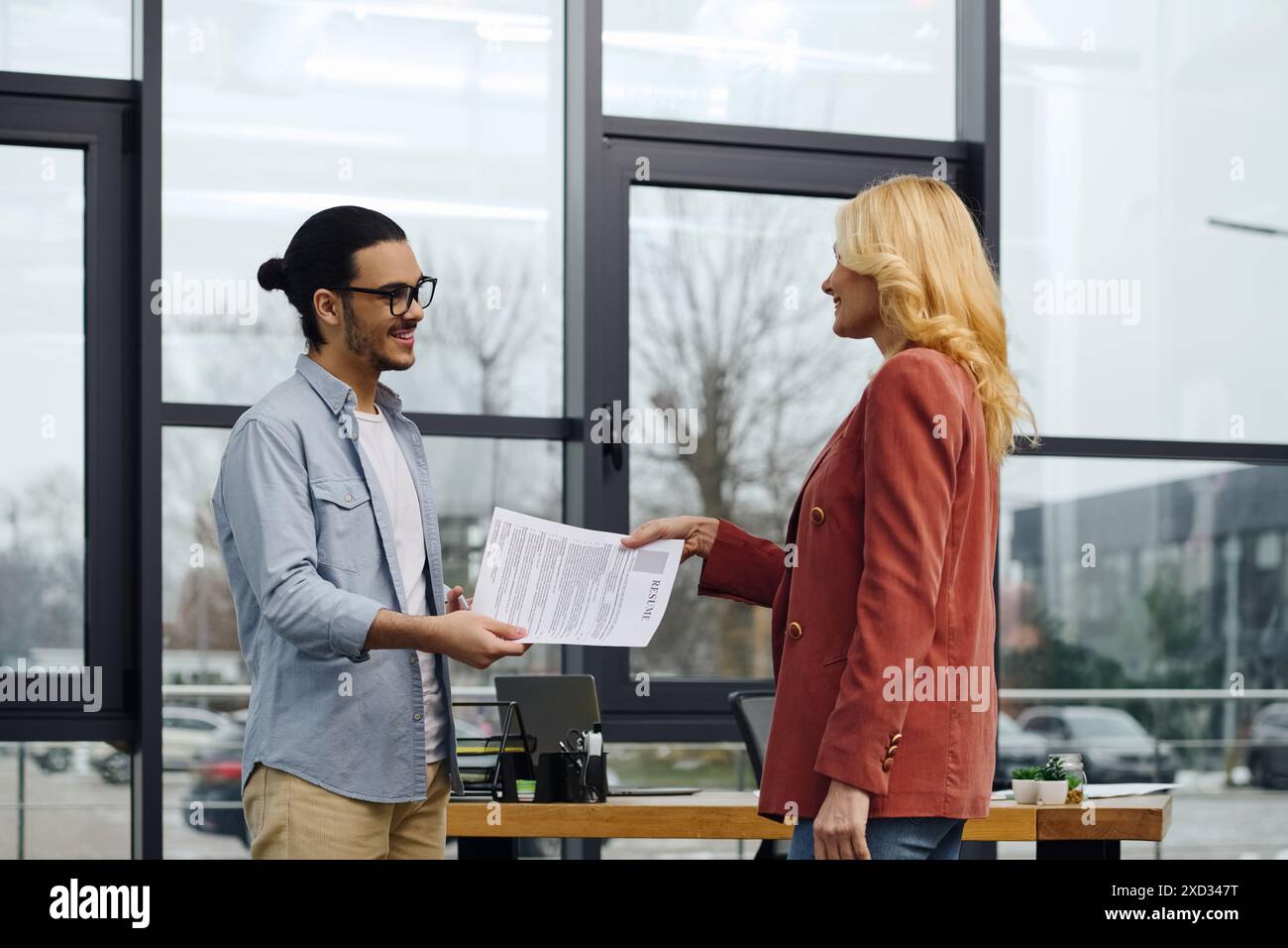 A man and woman exchanging documents by a window Stock Photo - Alamy