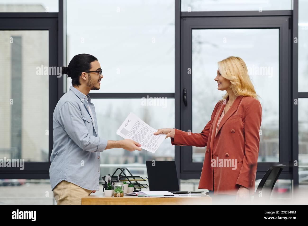 A man and woman exchanging documents in an office setting Stock Photo ...