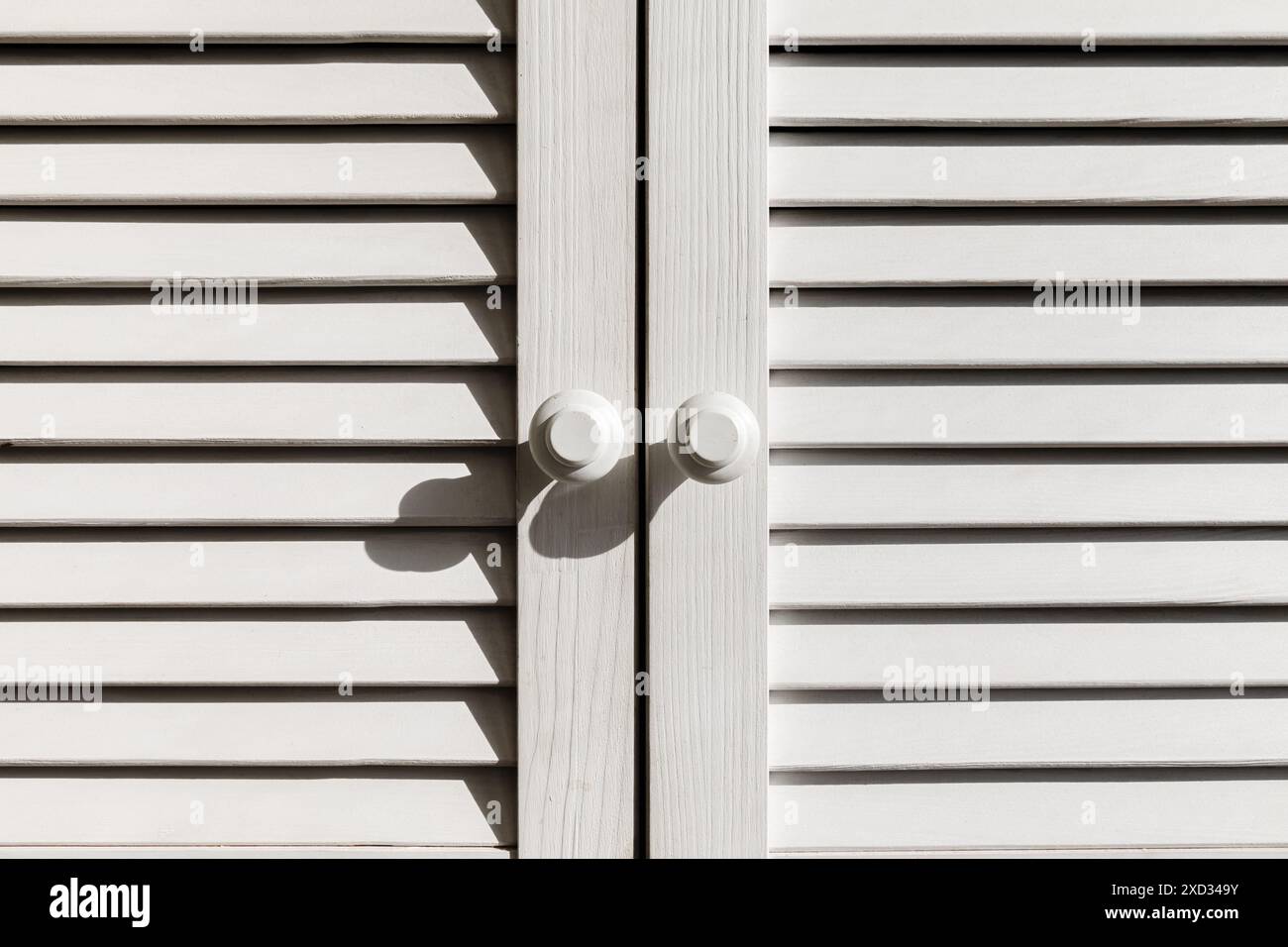 White wooden door with louvres. Light and shadows. Abstract texture ...