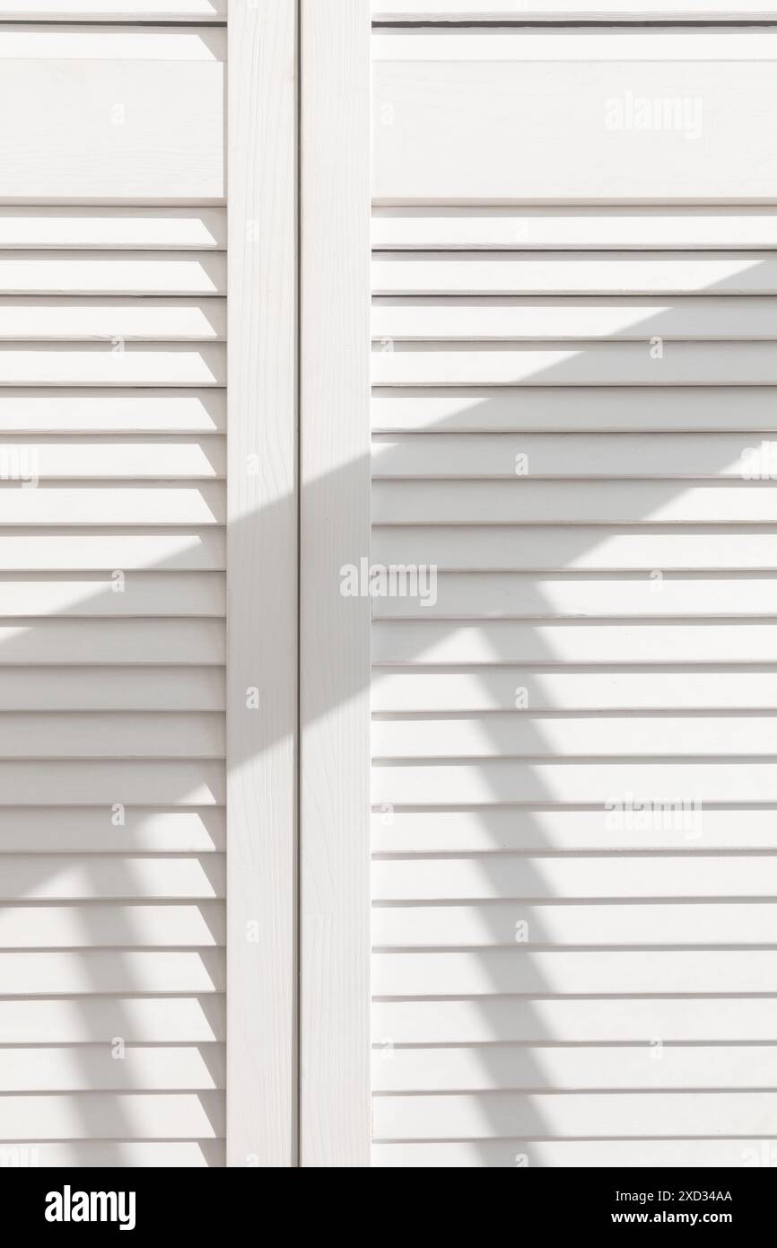 White wooden door with louvres. Light and shadows. Abstract texture ...