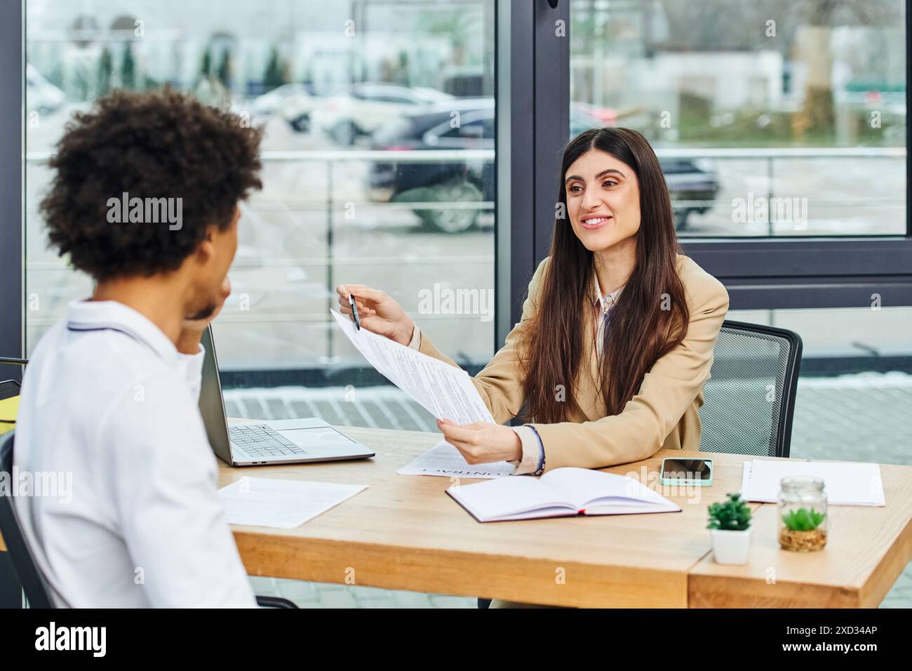 Man and woman engage in conversation at office desk during job ...