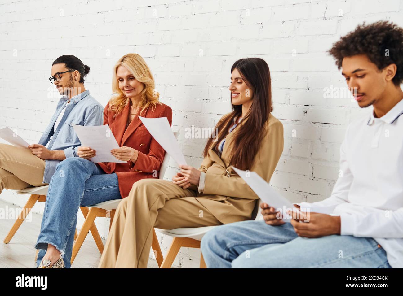 Diverse group reading papers while seated in chairs Stock Photo - Alamy