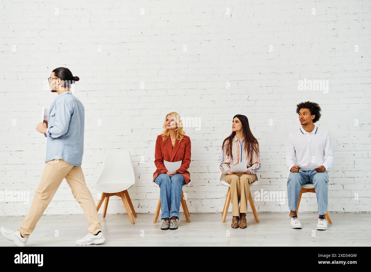 Group of people sitting in a row in front of a white wall Stock Photo ...