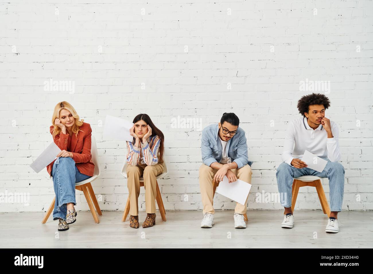 A diverse group of people sitting in front of a blank white wall ...