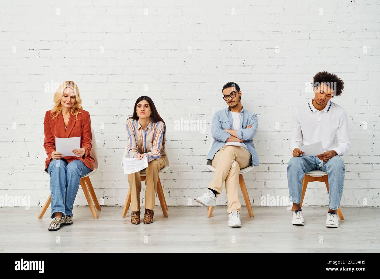 A group of people sitting gracefully on chairs in front of a white wall ...
