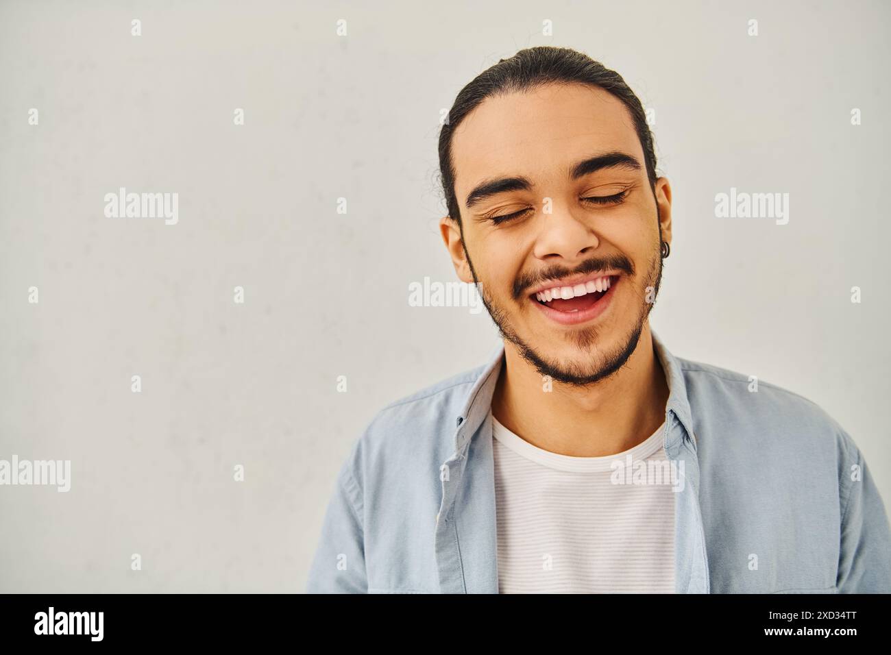 A young man laughs while looking at a blank white backdrop Stock Photo ... A young man laughs while looking at a blank white backdrop Stock Photo ...