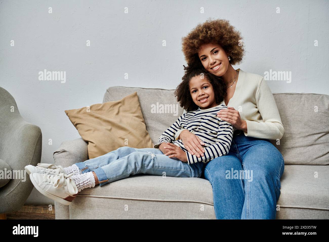 Happy African American mother and daughter spending quality time together, sitting comfortably ...