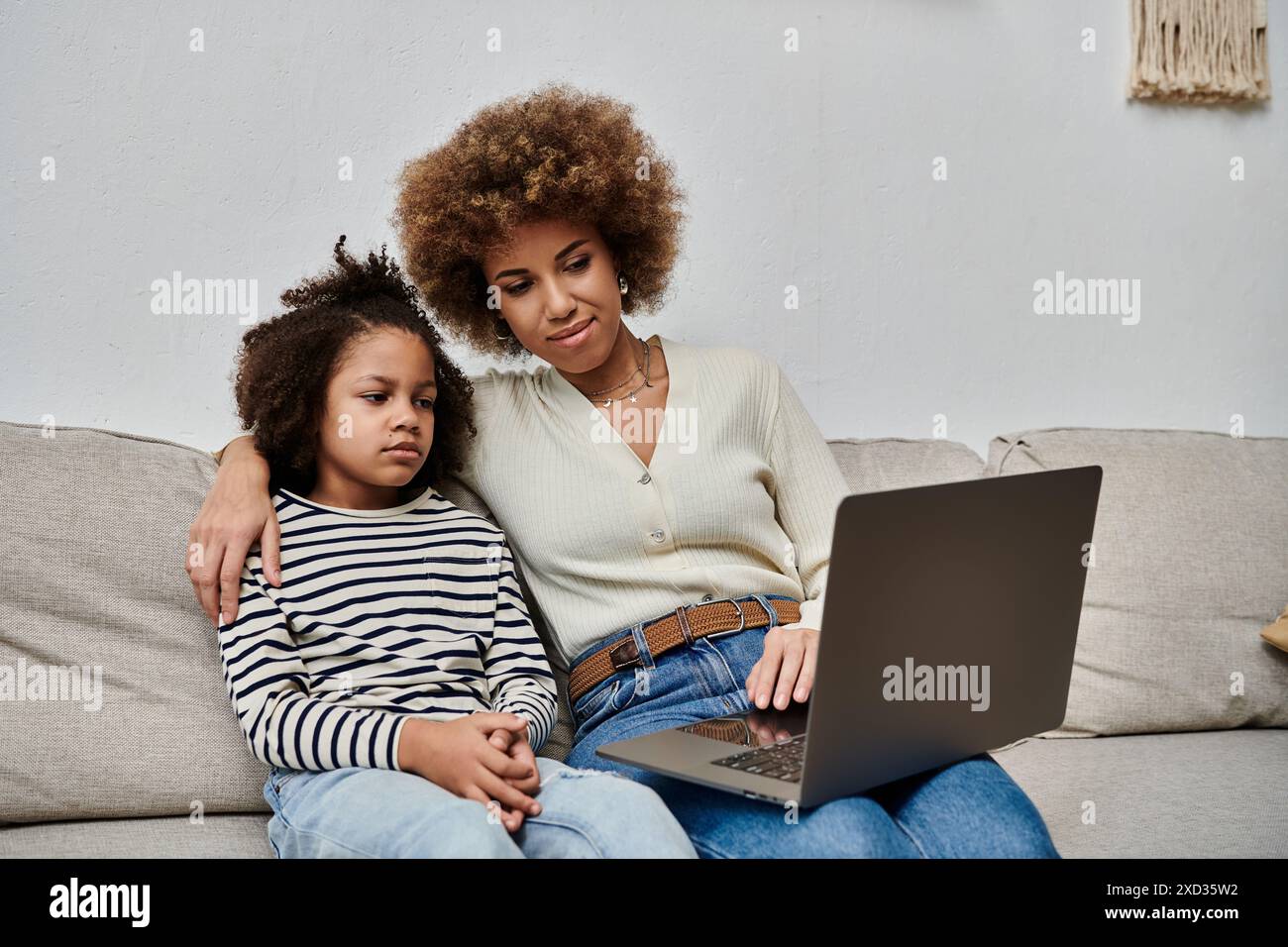 A happy African American mother and daughter sit on a couch using a laptop together Stock Photo ...