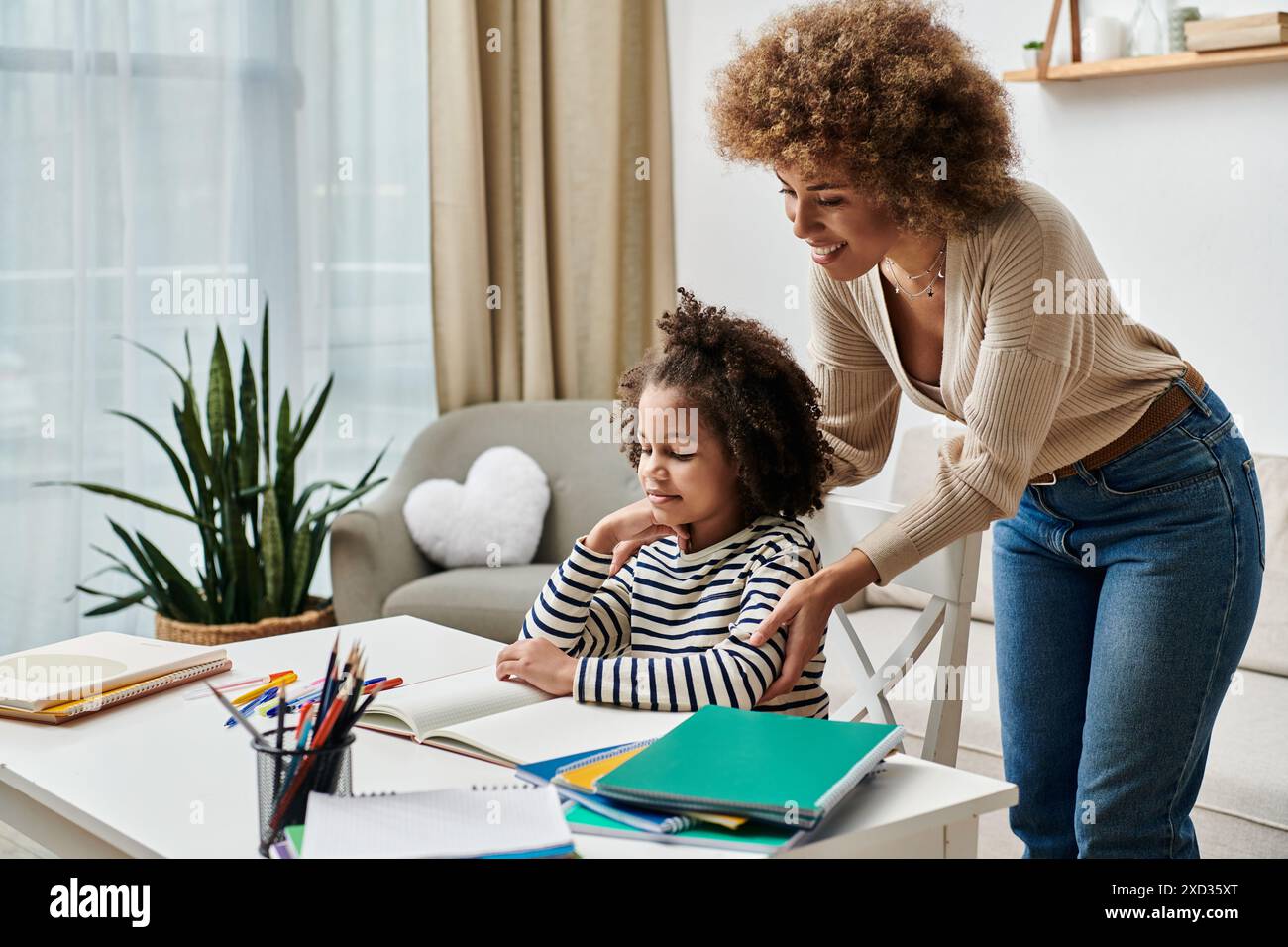 A happy African American mother helping her daughter with homework at ...