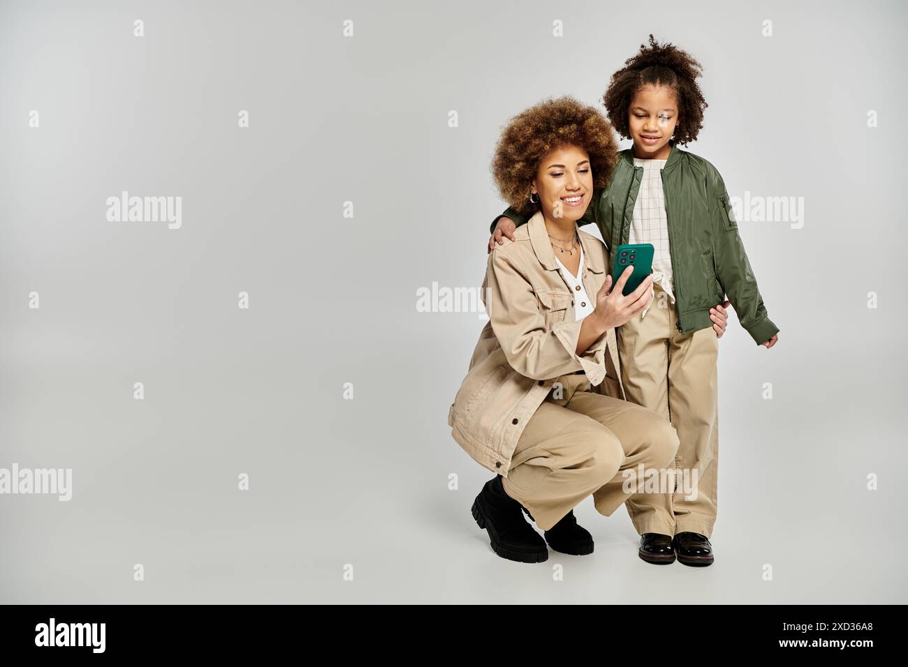 A curly African American mother and daughter in stylish clothes ...